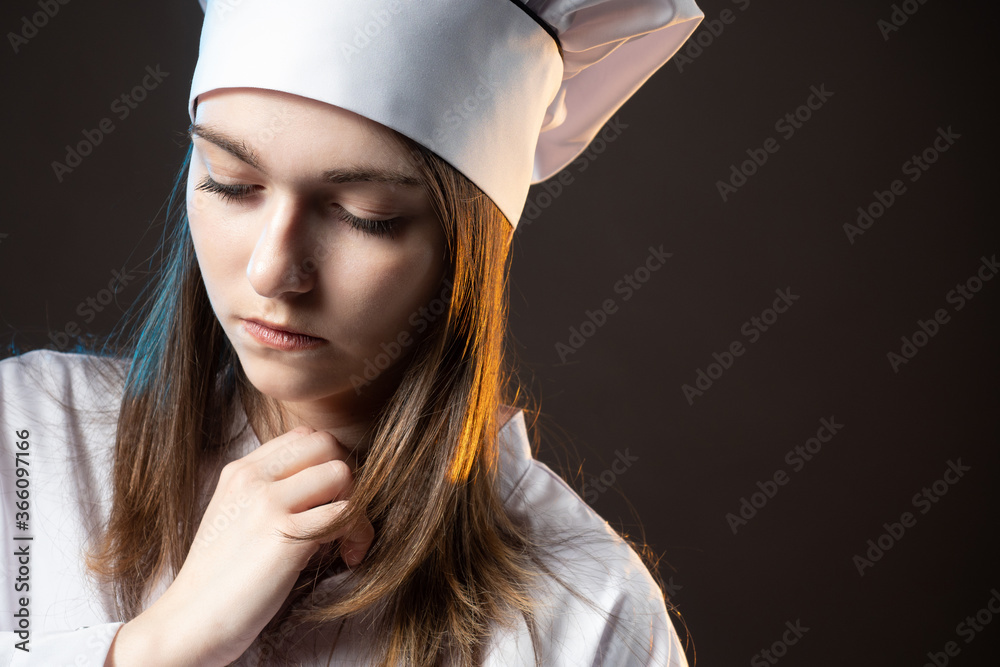 Sad Chef cook woman. Chef girl is somewhat upset. Woman cook on a black ...