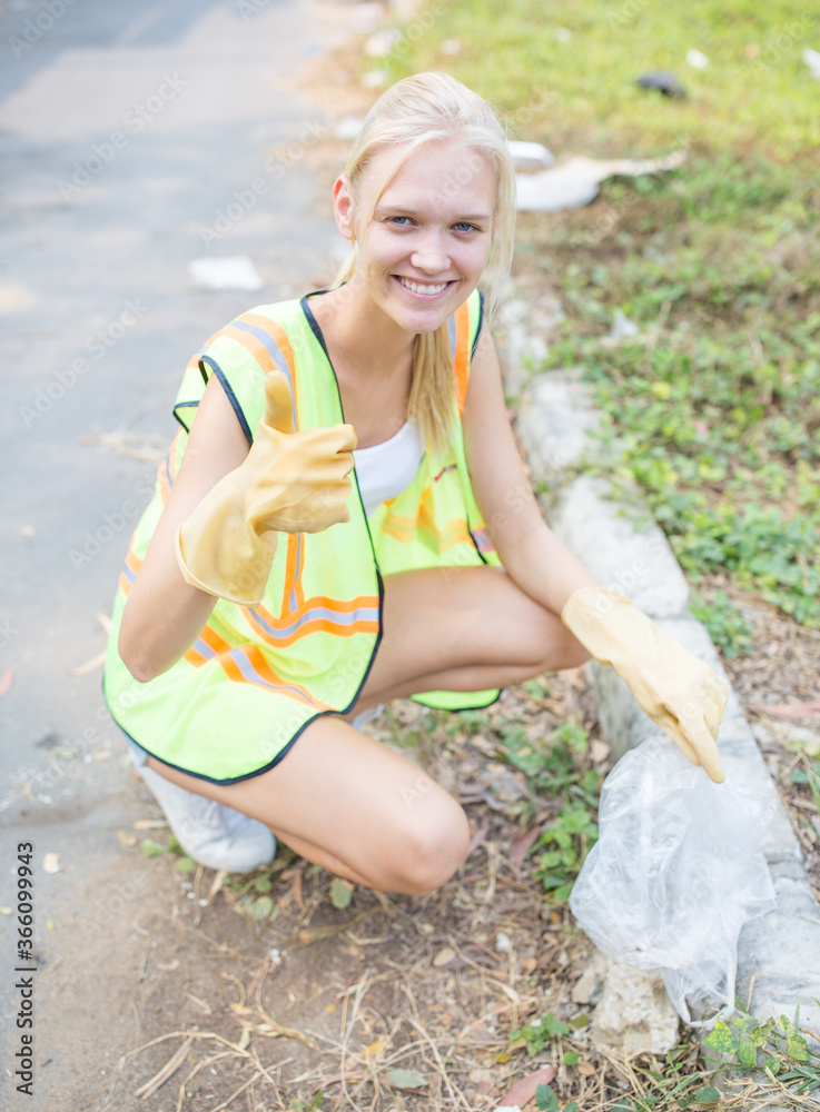 Happy female volunteer worker picking up plastic trash smiling and ...