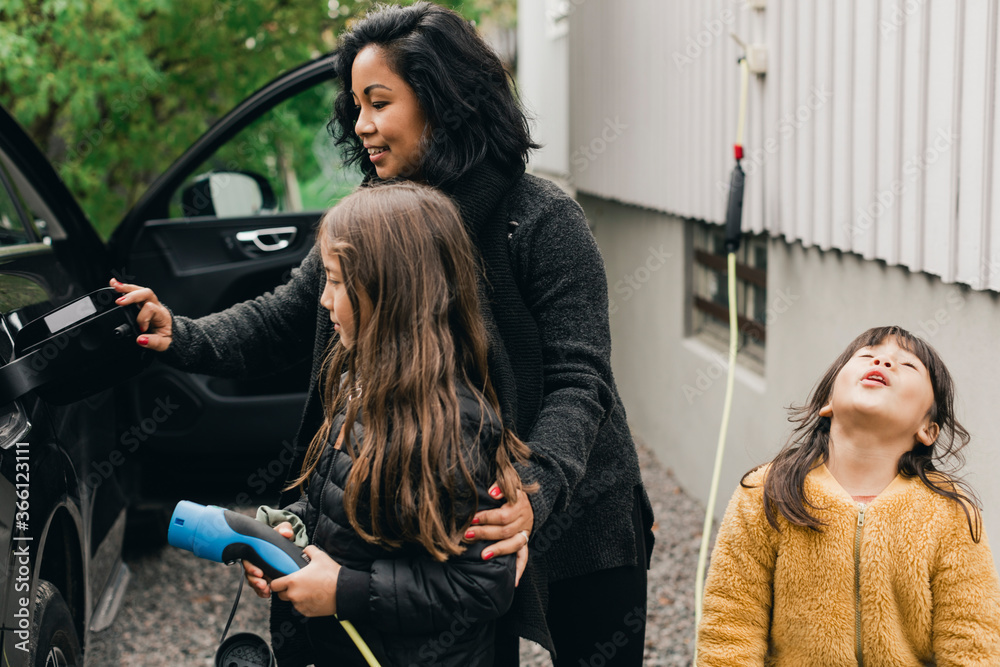 Woman teaching daughter to charge electric car at charging station ...