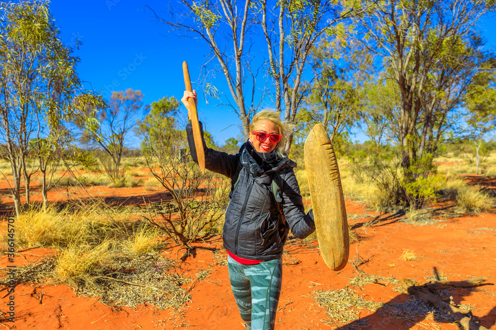 Happy tourist woman holding an aboriginal weapon of spear and a wooden ...