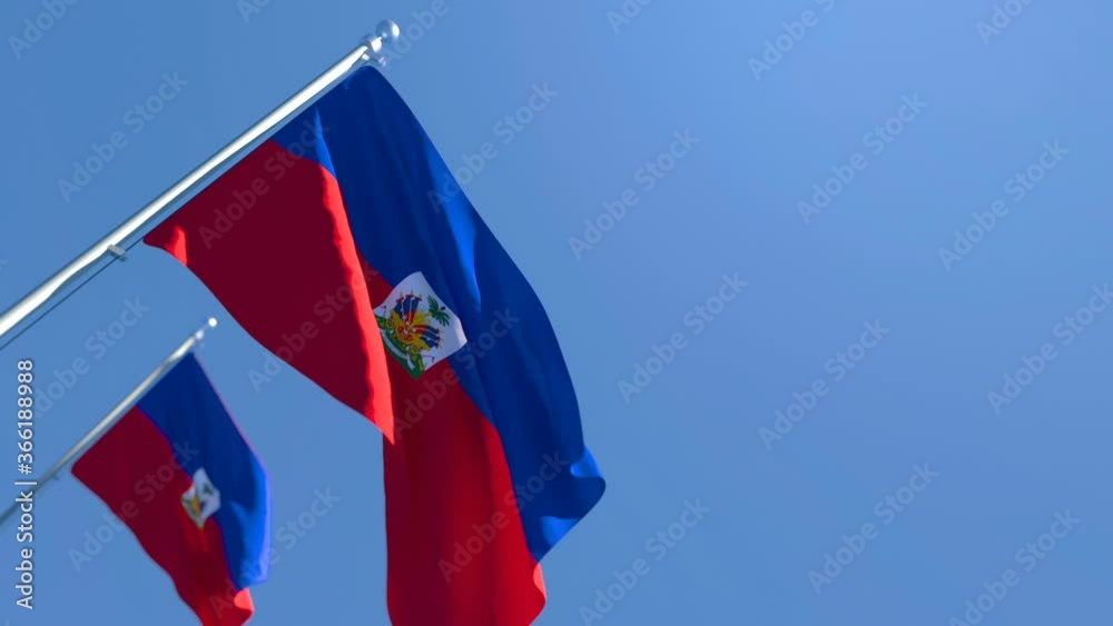 The national flag of Haiti is flying in the wind against a blue sky ...