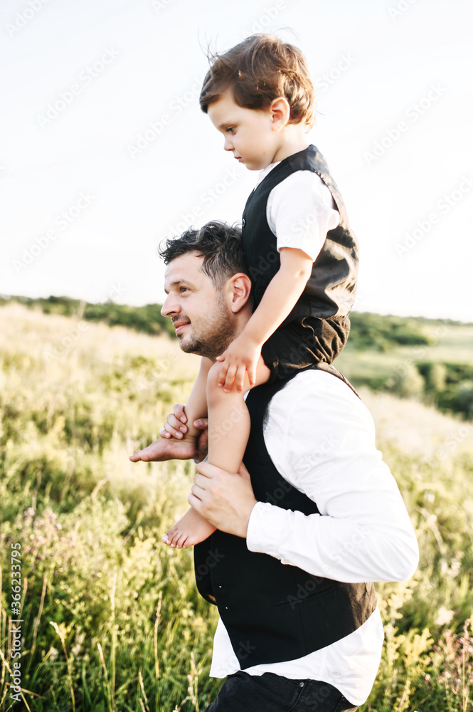 Vertical shot of young man with a boy on shoulders. Attractive young ...