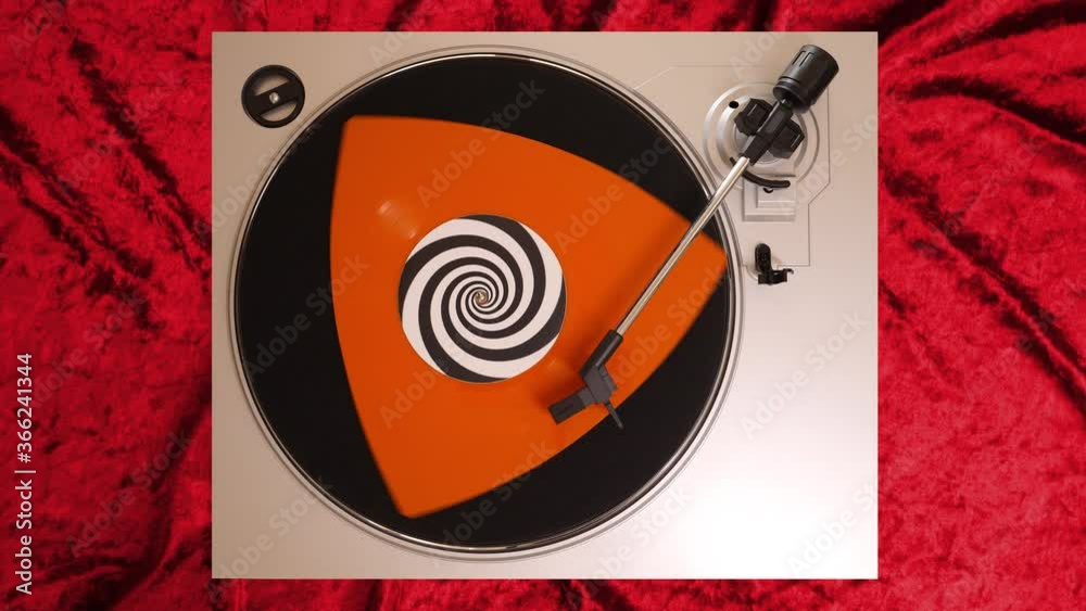 Orange shaped vinyl record on a DJ turntable with red velvet background ...