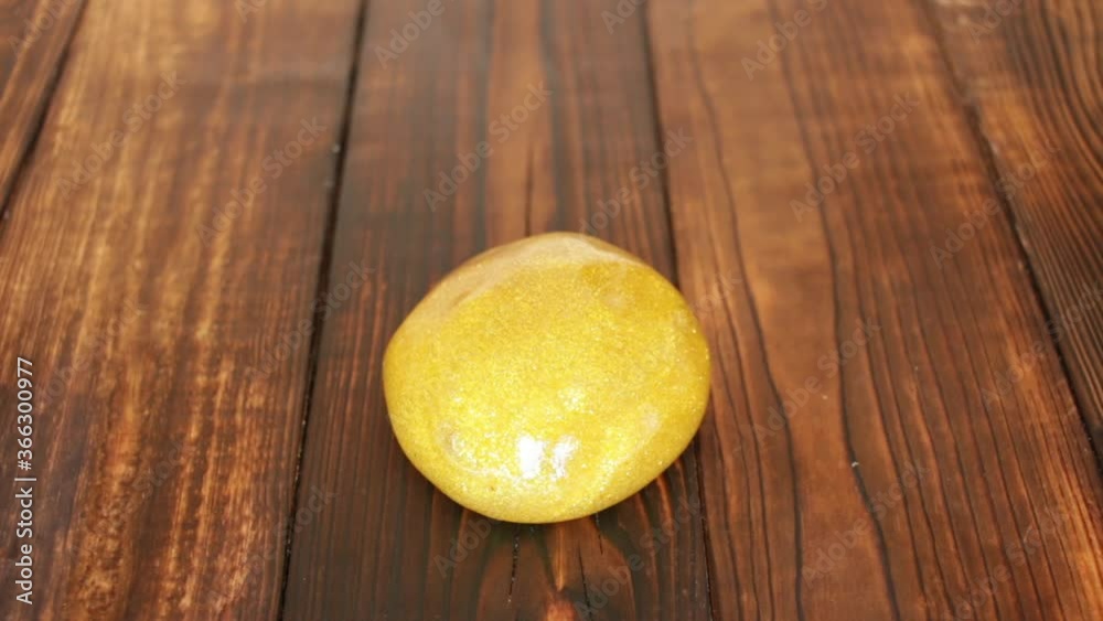 Yellow slime on a wooden brown background. A ball of slime spreads over ...