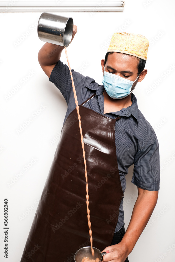 A picture of men preparing "teh tarik". Sweet milk tea been pull for mix well and create foam ...