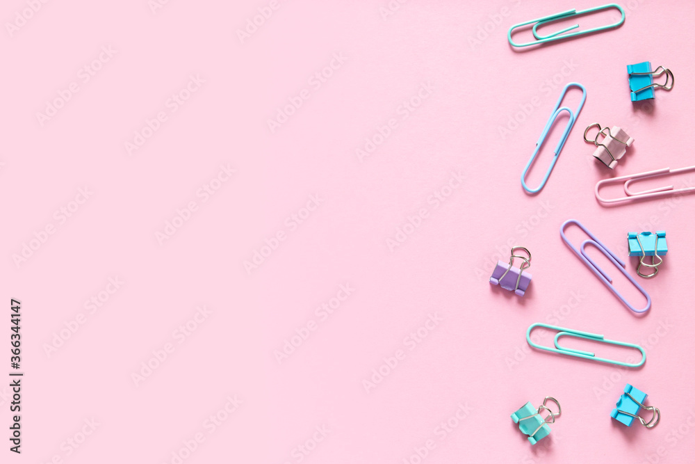 Back to school. Multi-colored paper clips laid out on a delicate pink ...