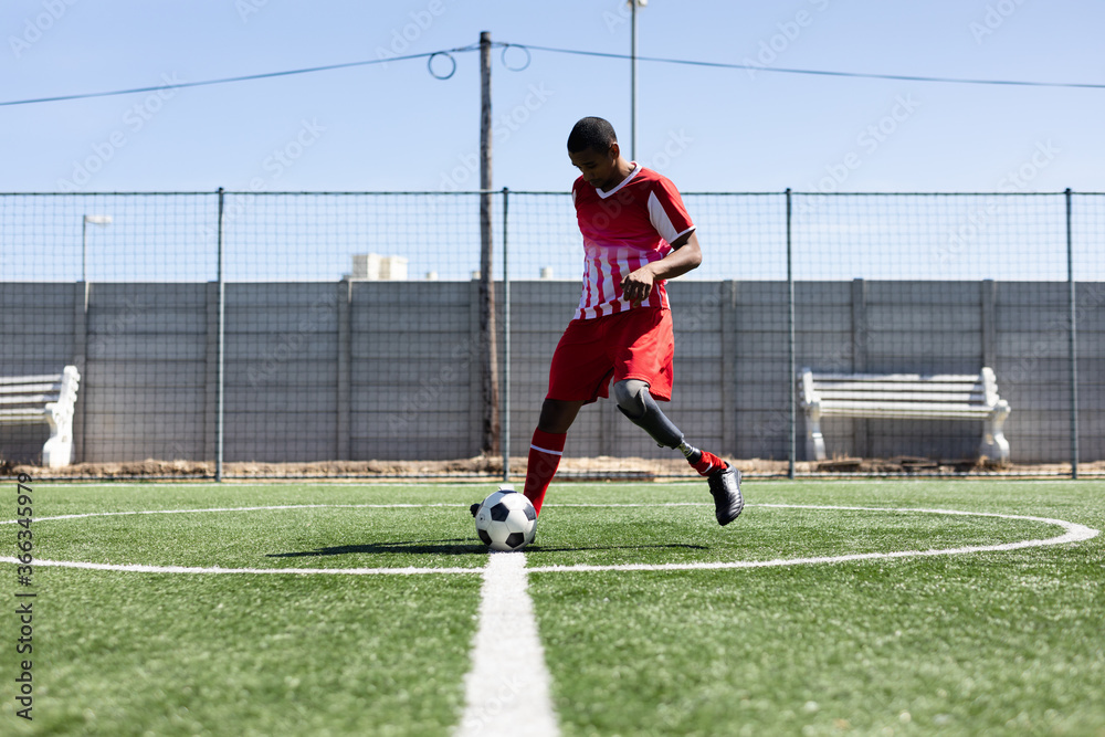 Mixed race male football player with prosthetic leg at a sports field ...