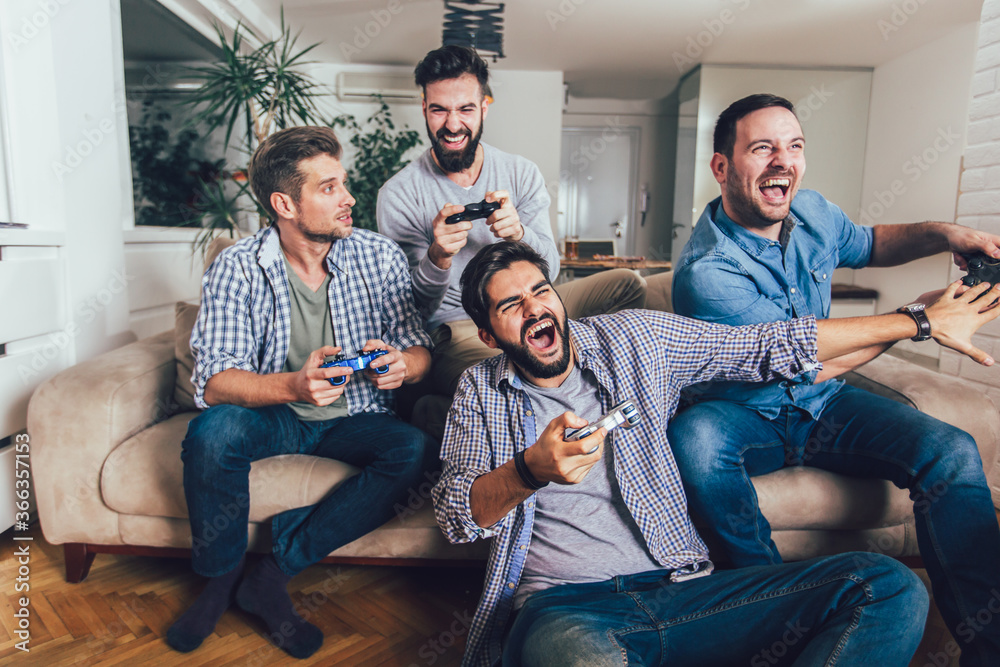 Smiling male friends playing video games at home and having fun. Stock ...