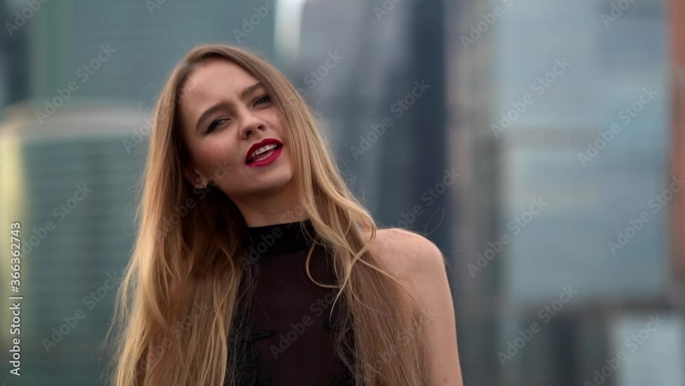 beautiful lady is singing song in city, standing at roof, skyscrapers ...
