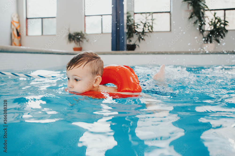 Cute Caucasian child boy in swimming pool with red float ring ...