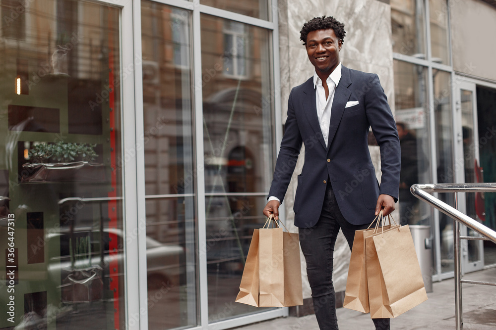 Black man in a city. Guy with shopping bags. Man in a black suit; Stock ...