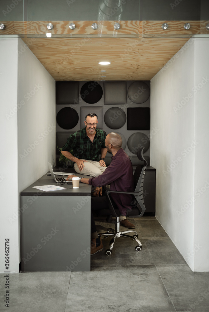 Two businessmen laughing while working together in an office cubicle ...