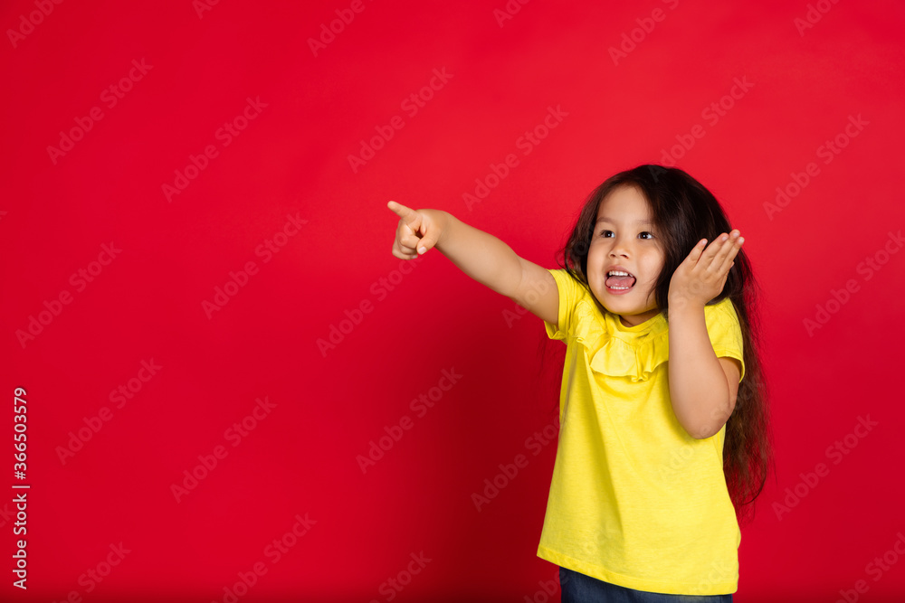 Shocked pointing. Beautiful little girl isolated on red background ...