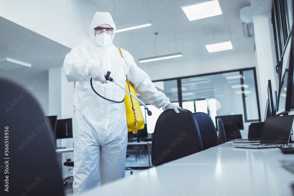 Office disinfection during COVID-19 pandemic. Man in protective suit ...