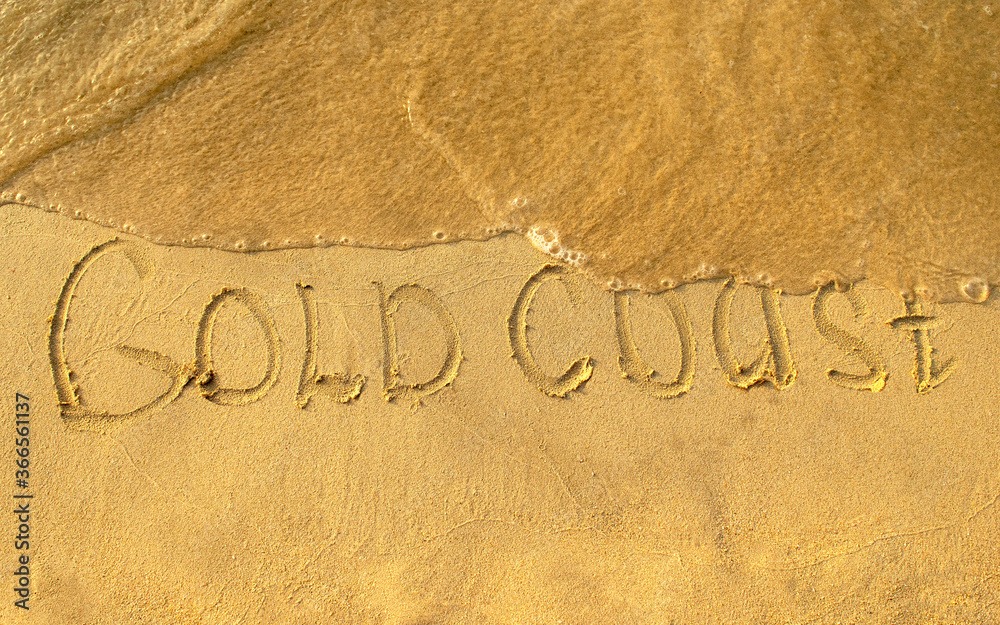 Gold Coast words written on beach sand with water wave. Gold Coast ...