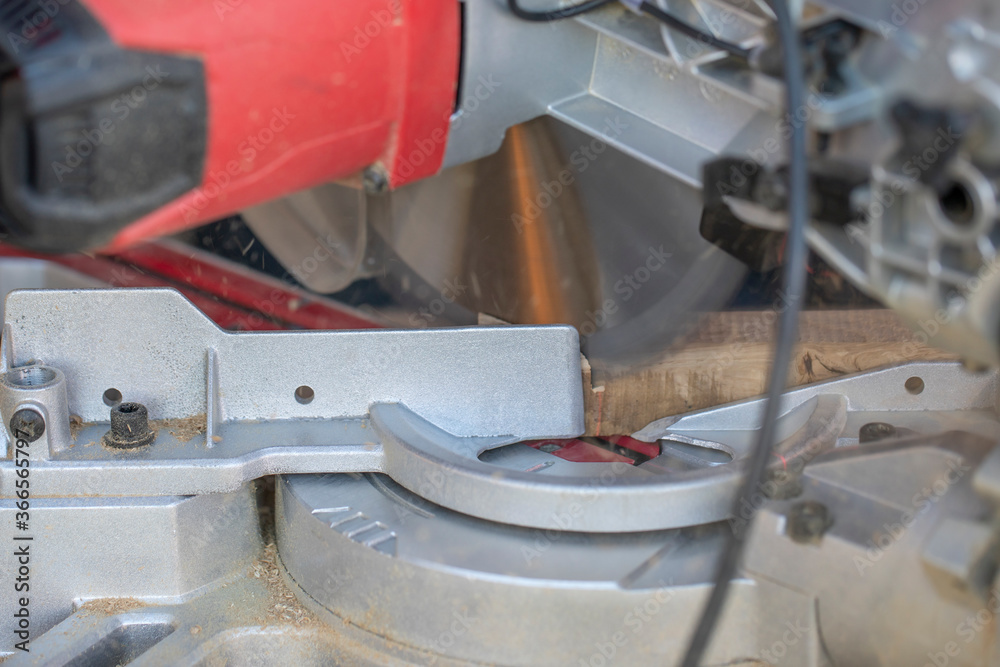 A sharp rotating circular saw blade cuts the oak beam into pieces. Wood ...