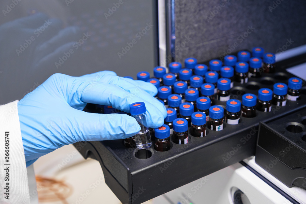 Close up woman hand in a rubber gloves put sample in a glass vial with ...