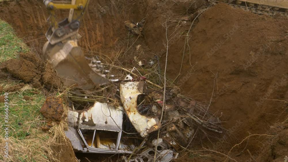 CLOSE UP: Excavator bucket crushes a rusty old car and shrub twigs ...