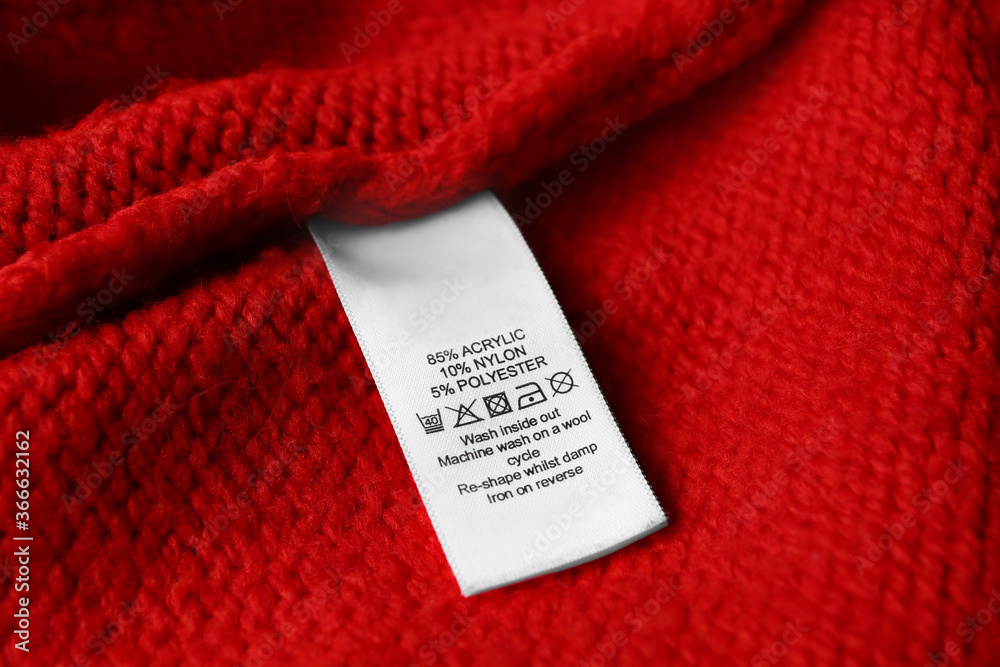 Clothing label with care symbols and material content on red sweater ...