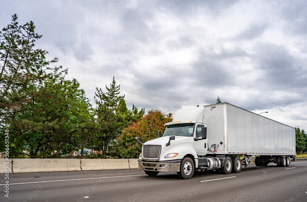 White big rig day cab semi truck with roof spoiler transporting goods ...
