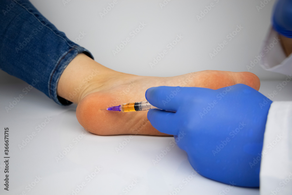 An orthopedic surgeon gives an injection in the heel to relieve pain ...