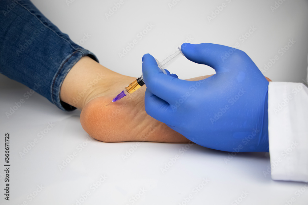 An orthopedic surgeon gives an injection in the heel to relieve pain ...