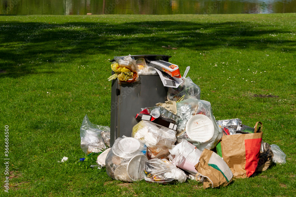 mit Abfall und Plastik Verpackungen übervoller Mülleimer steht auf ...