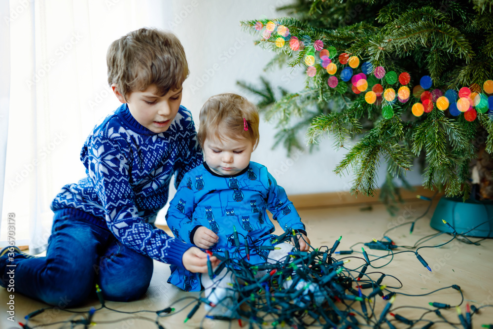 Cute baby girl and kid boy taking down holiday decorations from ...