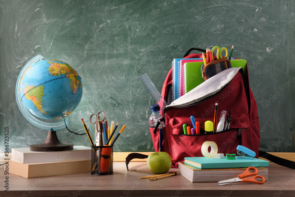 School desk with school supplies and blackboard background front view ...