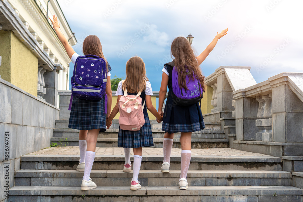 schoolkids in school uniforms go up the stairs to school against the ...