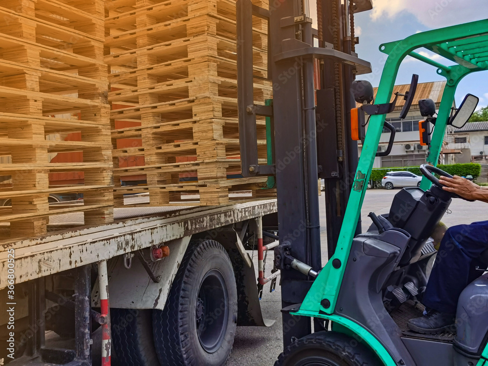 Worker driving forklift to loading and unloading wooden pallets from ...