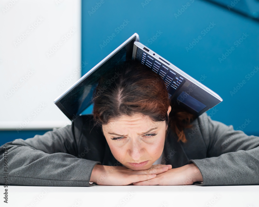 Problems at work. An exhausted woman folded her laptop over her head at ...