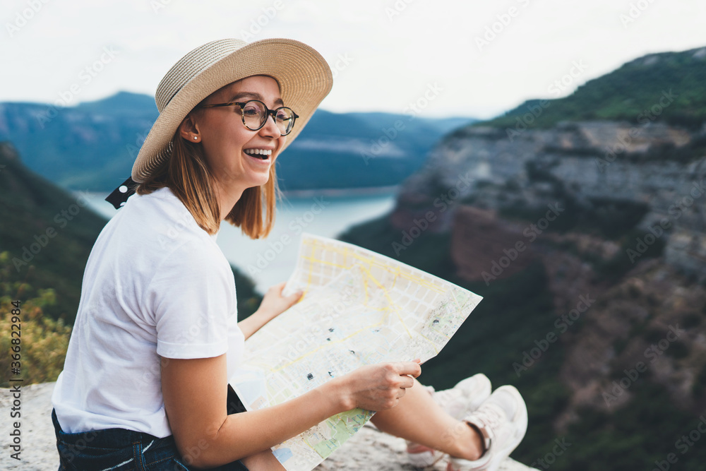 laughing young blonde tourist holds in hands map of landscape and looks ...