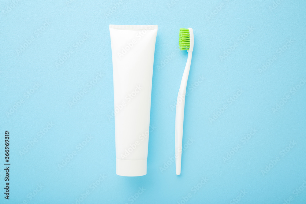 Toothbrush with green bristles and white tube of toothpaste on light ...