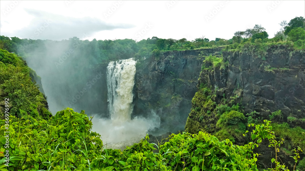 The unique Victoria Falls. A powerful stream falls into a steep rocky ...