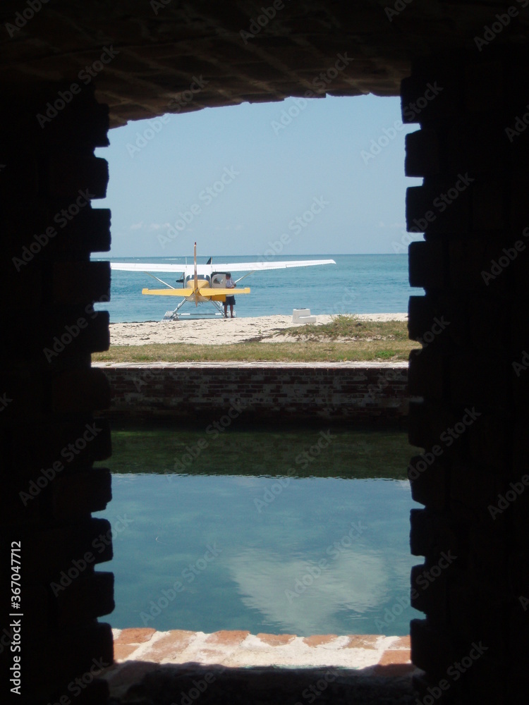 Sea plane on Caribbean beach viewed through window of old island fort ...