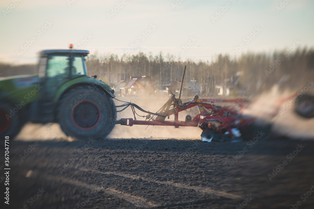 Tractor with a disc harrow system harrows the cultivated farm field ...