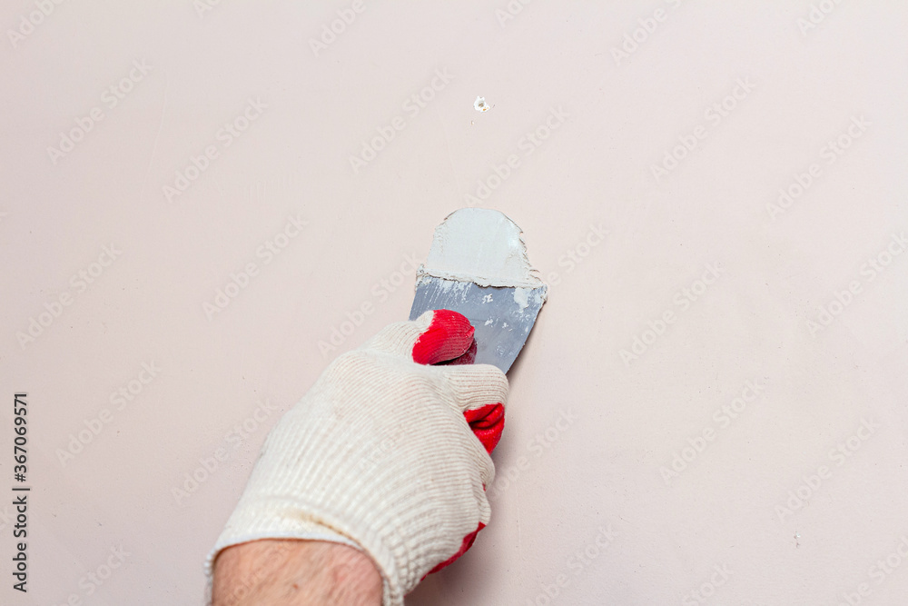 Puttying, sealing cracks with gypsum plaster using a spatula. Damaged ...