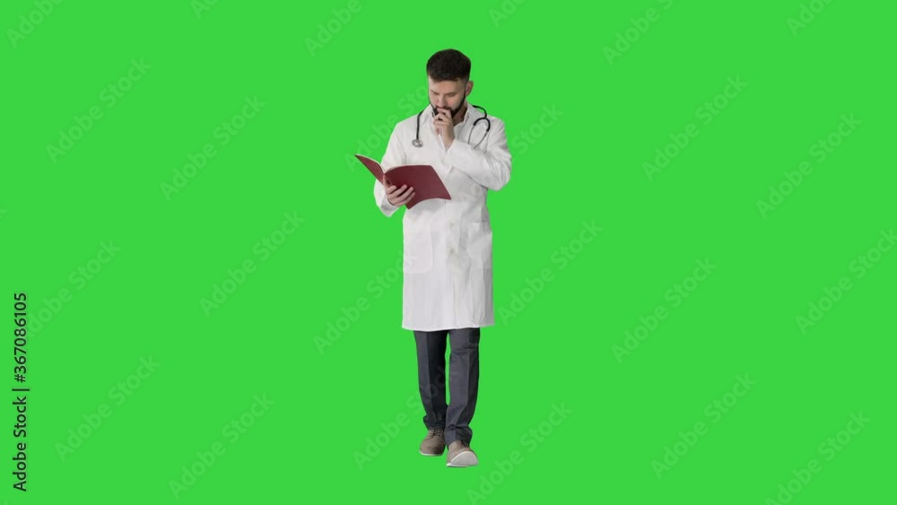 Doctor reading a book or a journal while walking on a Green Screen ...