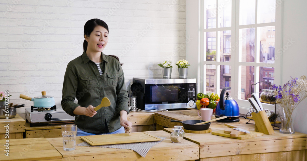 cheerful korean woman having fun in kitchen before prepare healthy meal ...