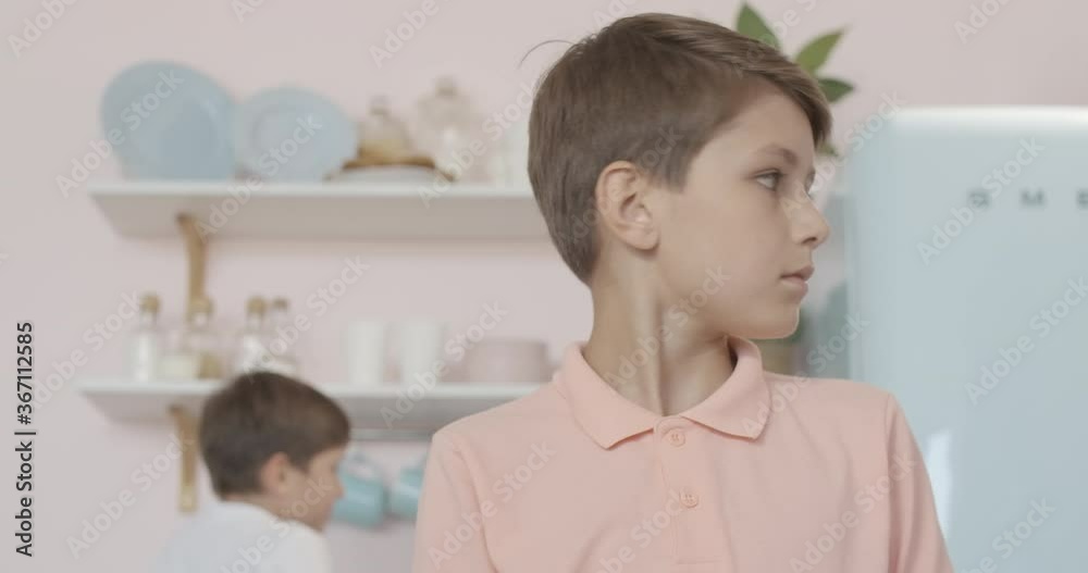 Close-up of confused Caucasian boy looking around as his twin brother ...