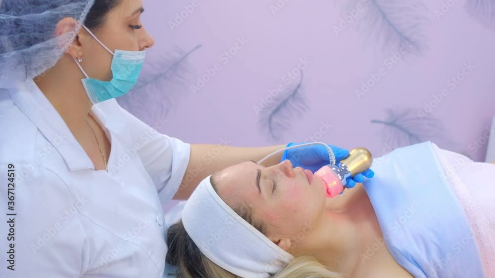 Cosmetologist doctor making phonophoresis procedure on woman face with ...