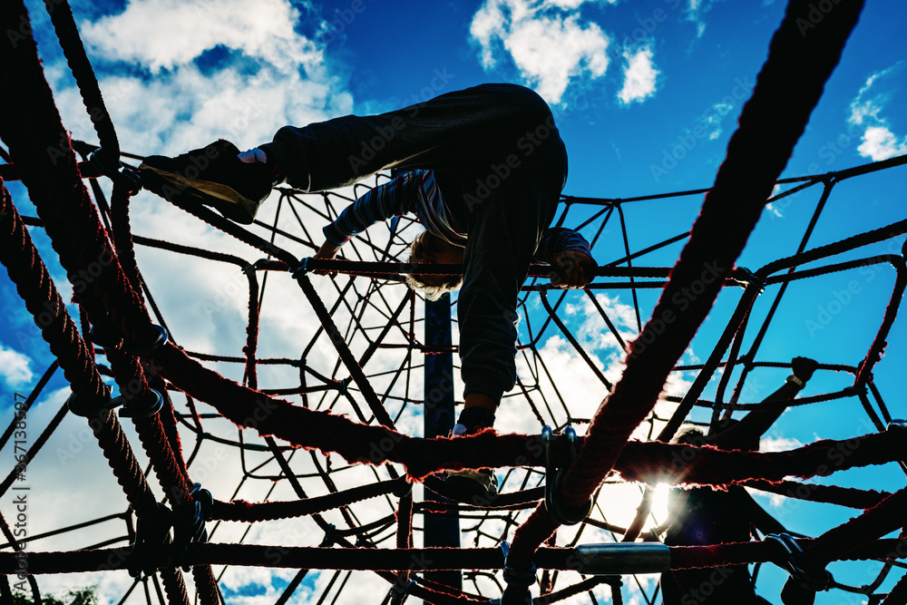 Silhouette of children playing in a park, climbing on some ropes living ...