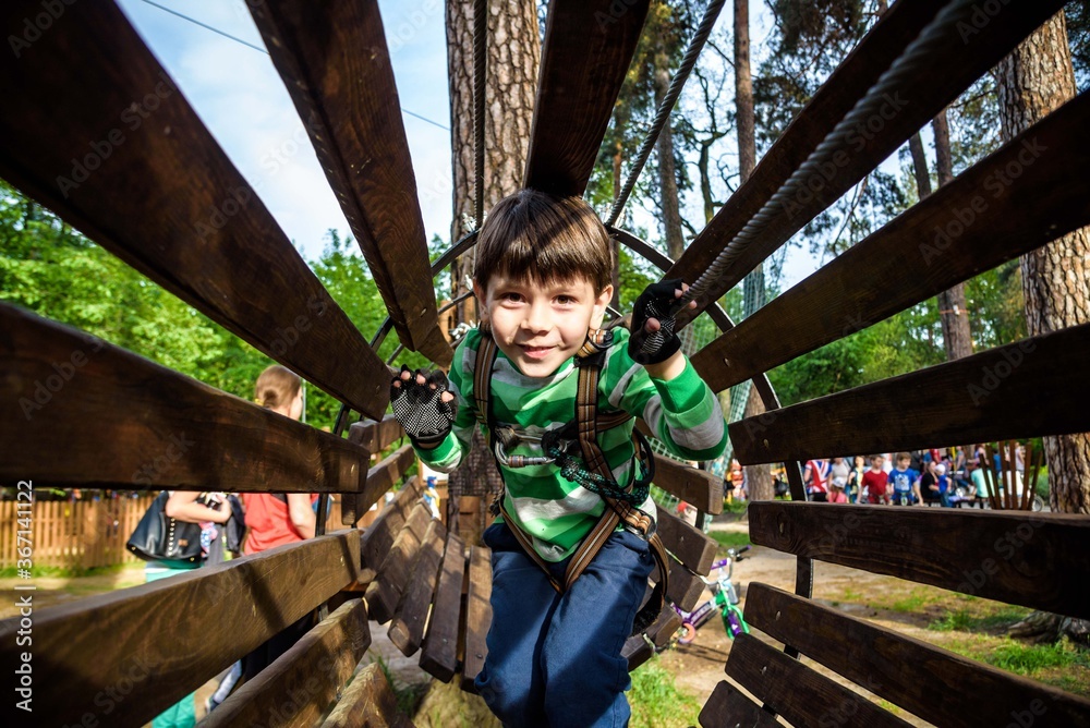 Little boy playing at rope adventure park. Summer holidays concept ...