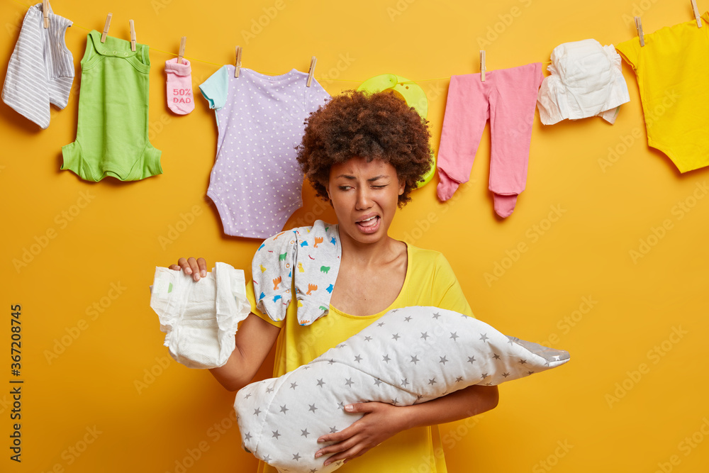 Busy responsible mother feels aversion as changes diaper, takes care of ...
