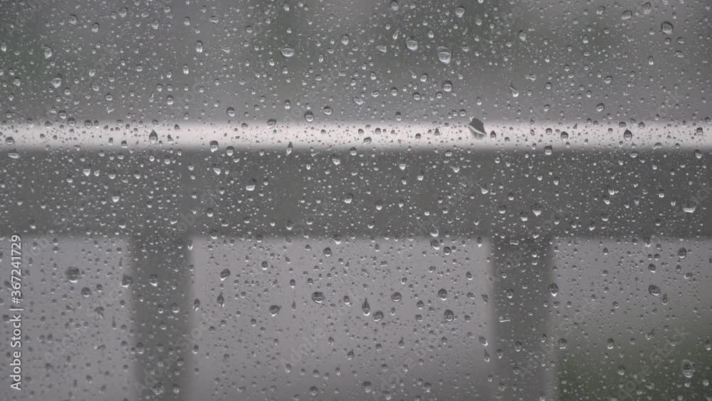 Raindrops Dripping On The Surface of Glass Window on blury background ...
