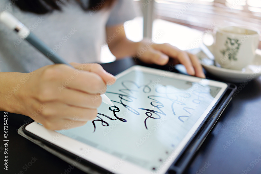 A female using Apple Pencil drawing hand lettering on a iPad using ...