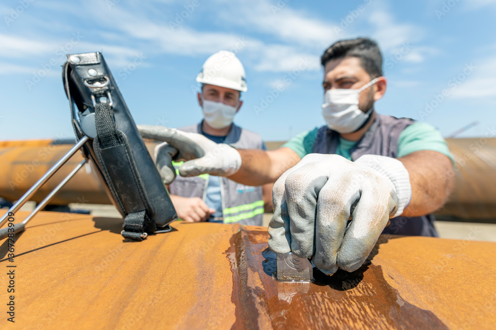 Technicians test a pipeline weld for defects using ultrasonic ...
