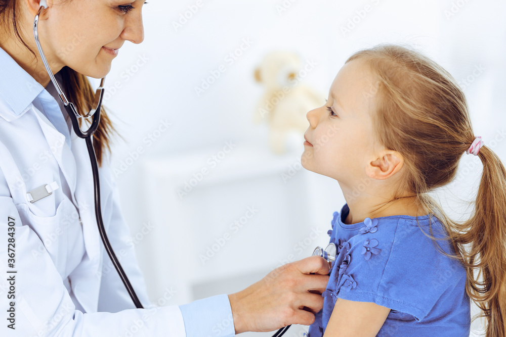 Doctor examining a little girl by stethoscope. Happy smiling child ...