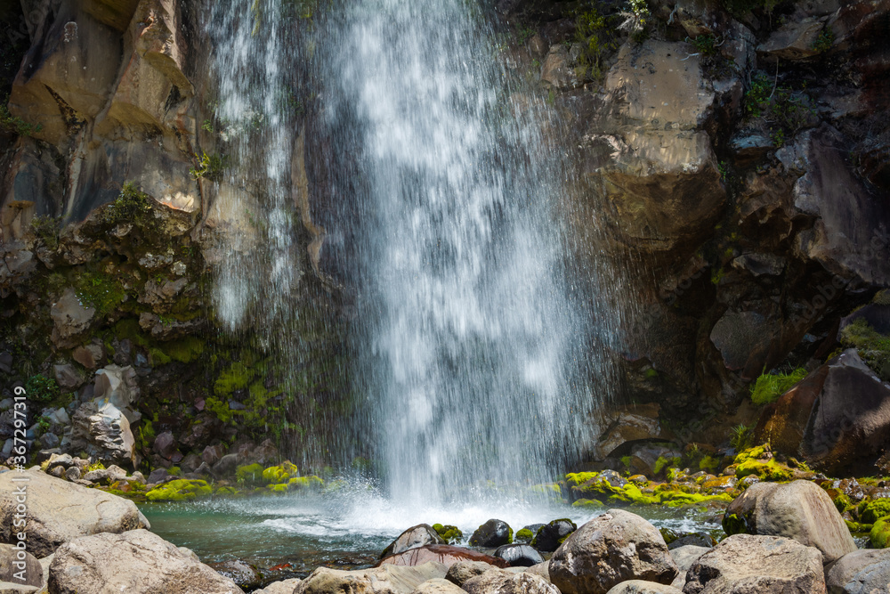 Powerfull stream of Taranaki falls falling into a shallow rock pool ...